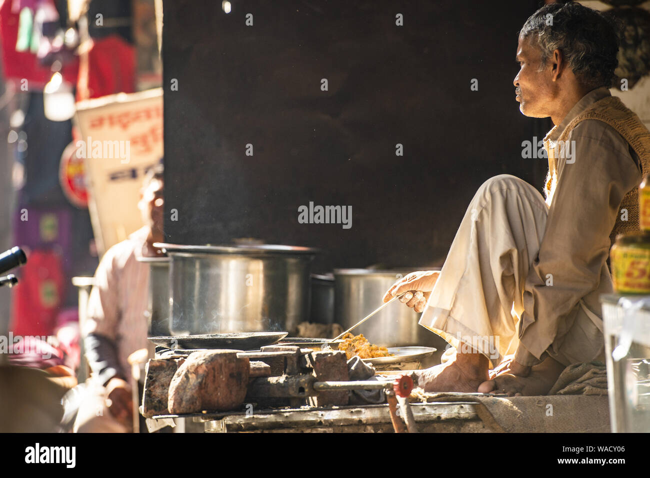 An Indian elderly man is cooking Chapati on the streets of Jaipur ...