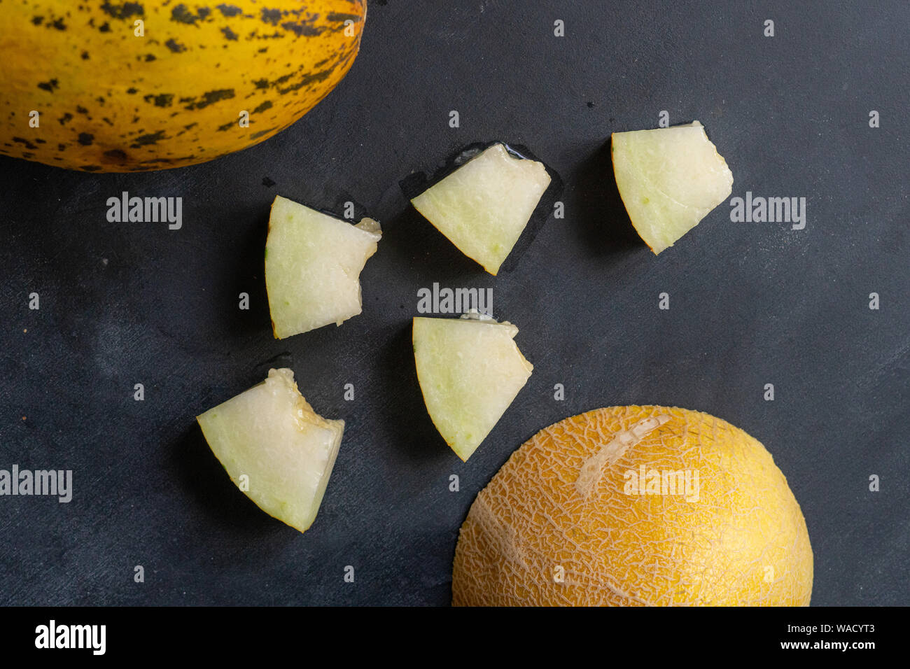 top view of fesh melon sliced pieces, cut on a black surface Stock ...