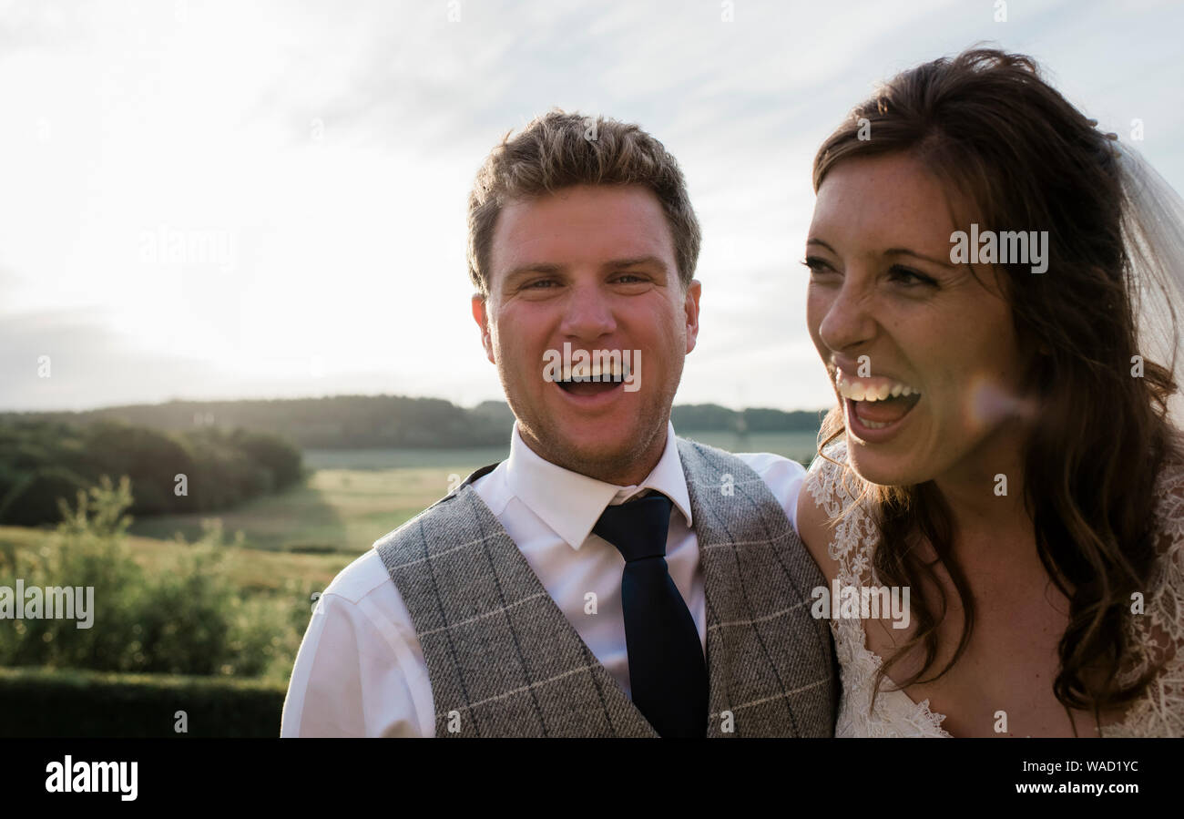 Newly married couple, bride and groom laughing on their wedding day ...