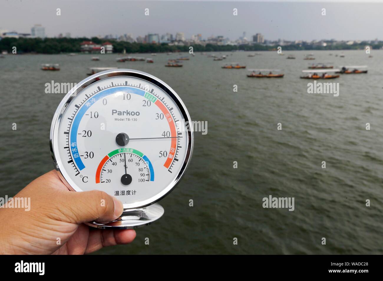 A local resident displays a thermometer showing the current temperature ...