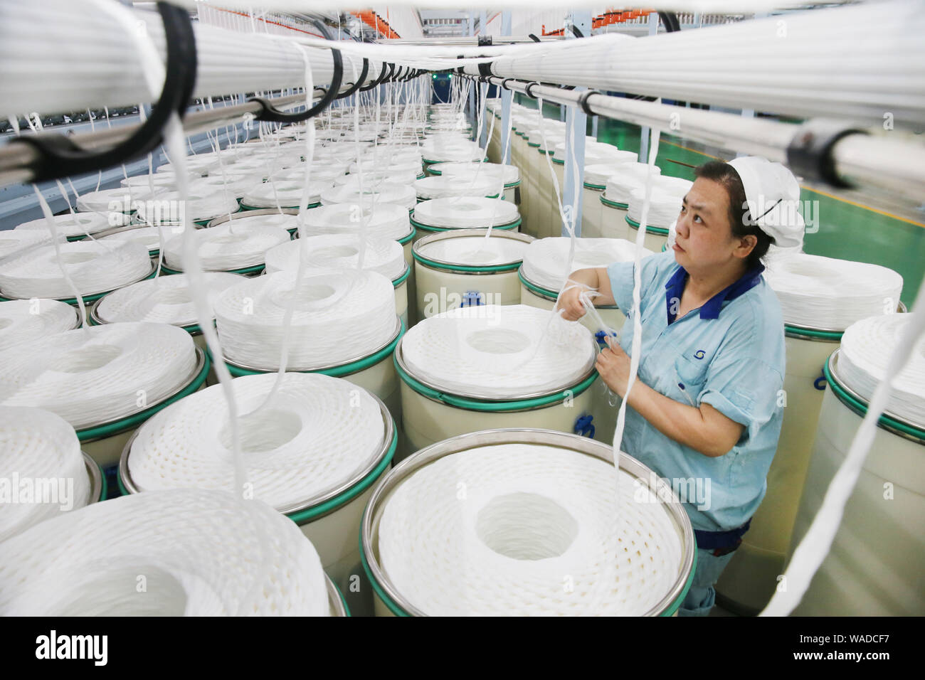 A female Chinese worker handles production of yarn at the textile factory of Jiangsu Dasheng ...