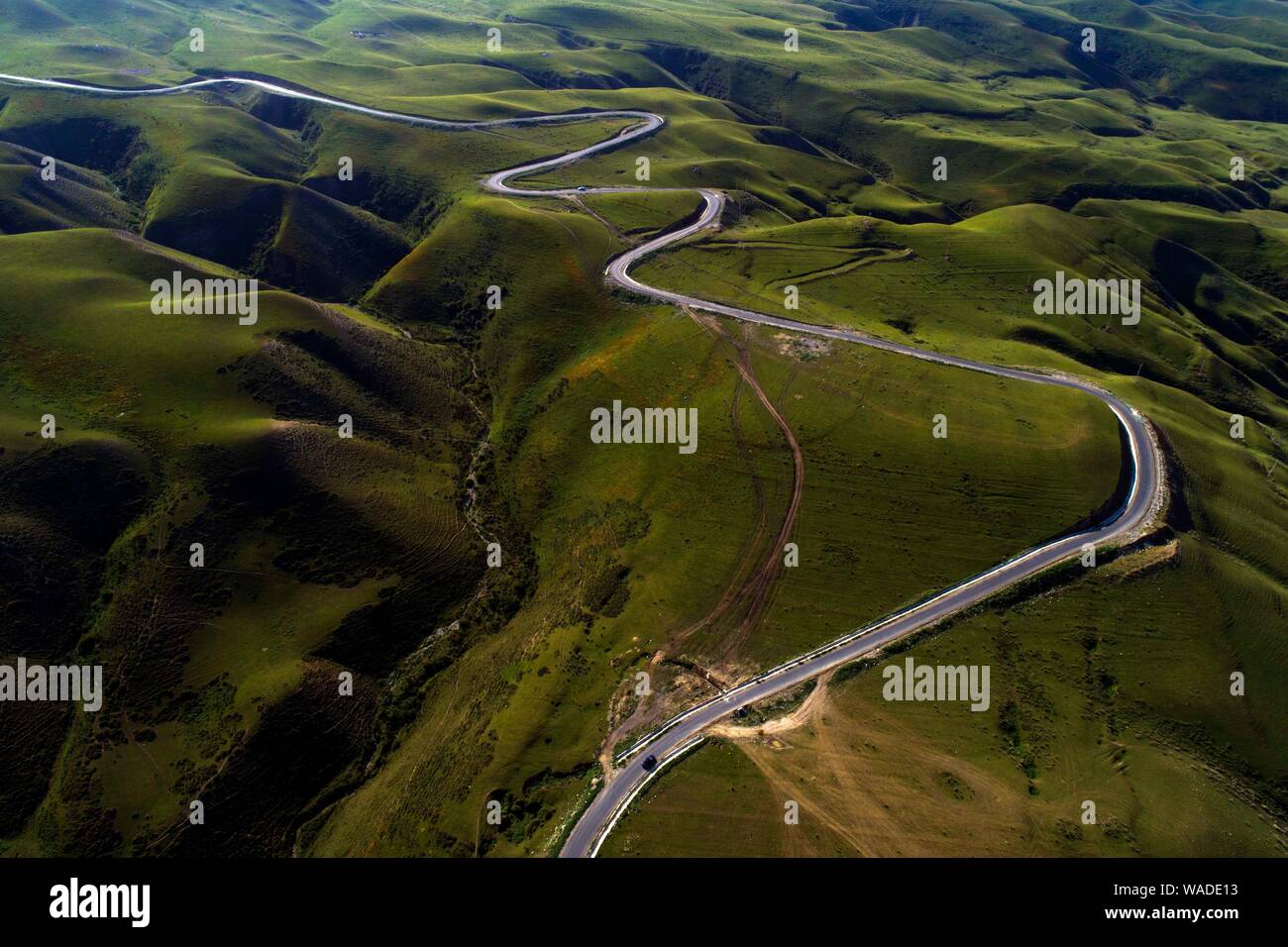 Cars drive on a spiral undulating mountain road at the Kalajun Scenic ...