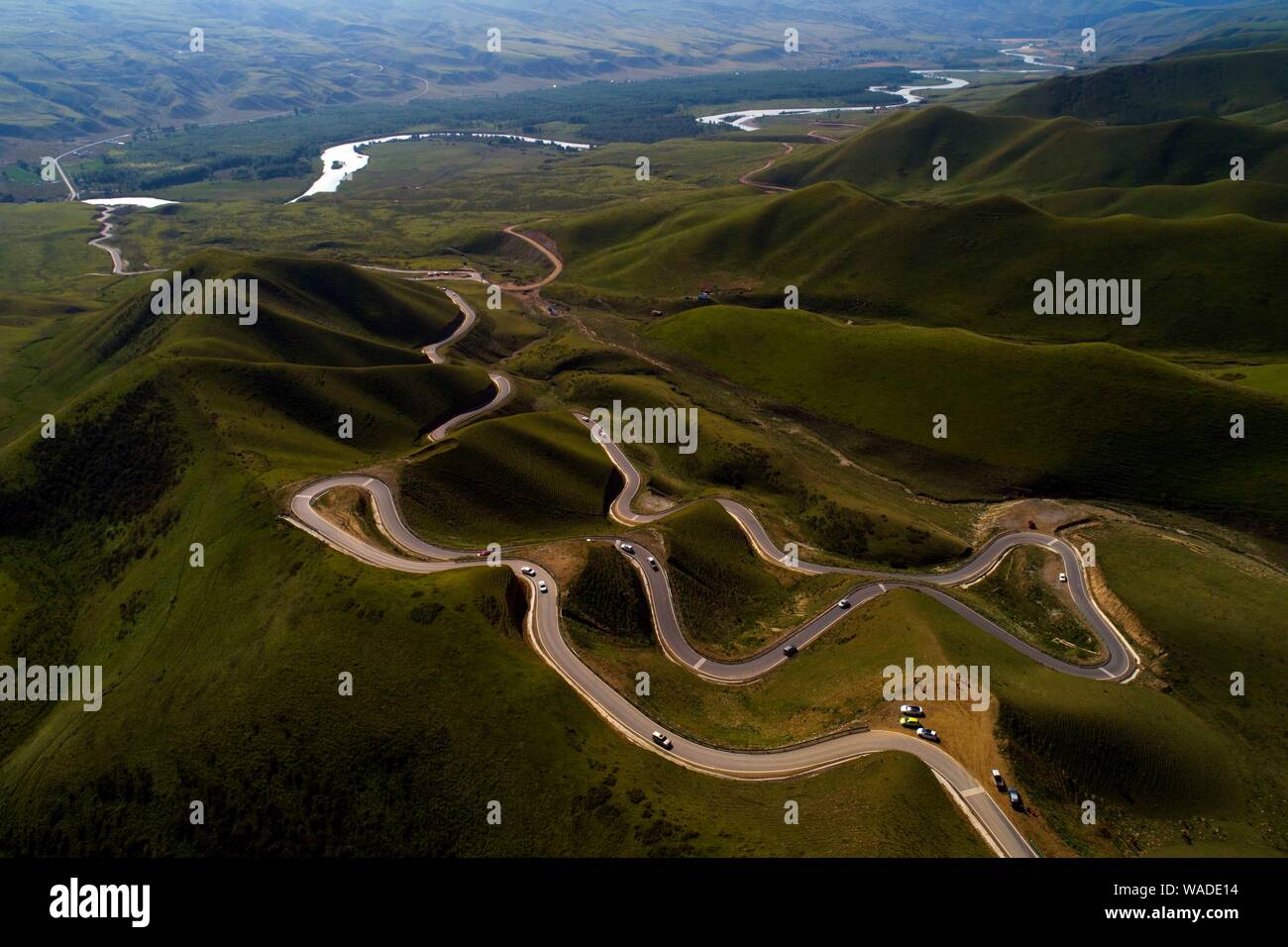 Cars drive on a spiral undulating mountain road at the Kalajun Scenic ...