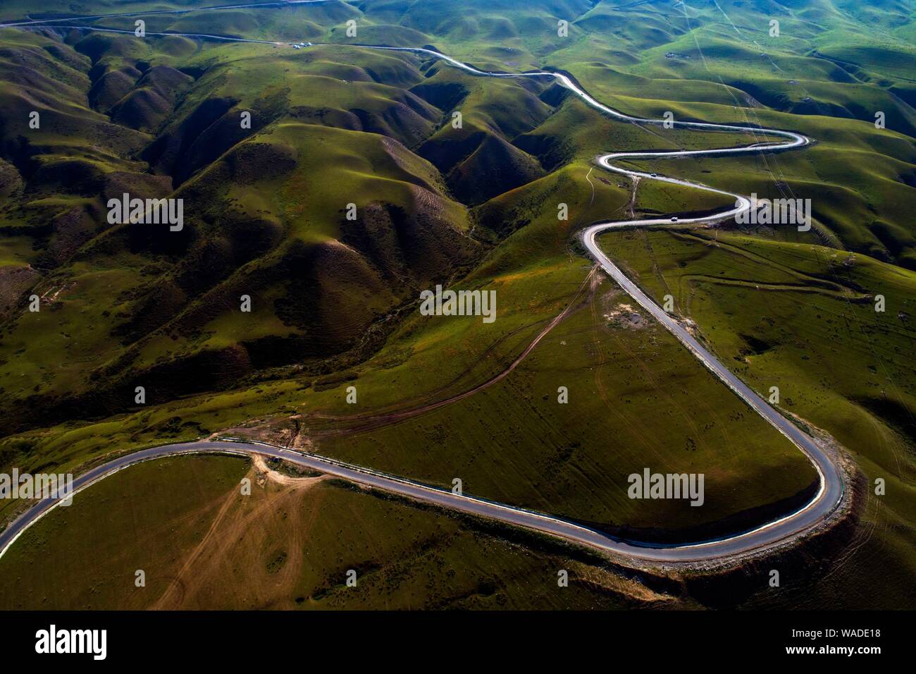 Cars drive on a spiral undulating mountain road at the Kalajun Scenic ...