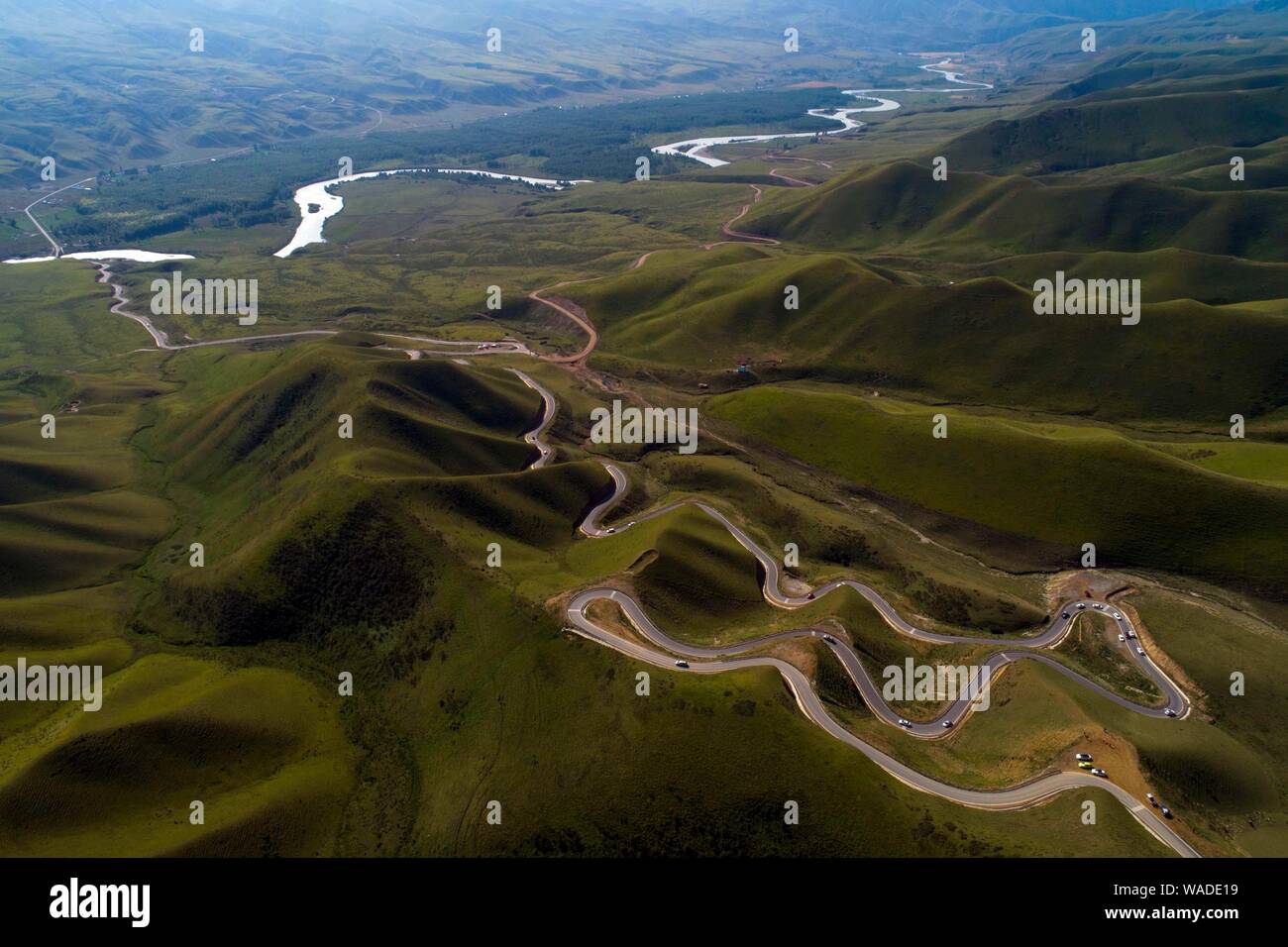 Cars drive on a spiral undulating mountain road at the Kalajun Scenic ...