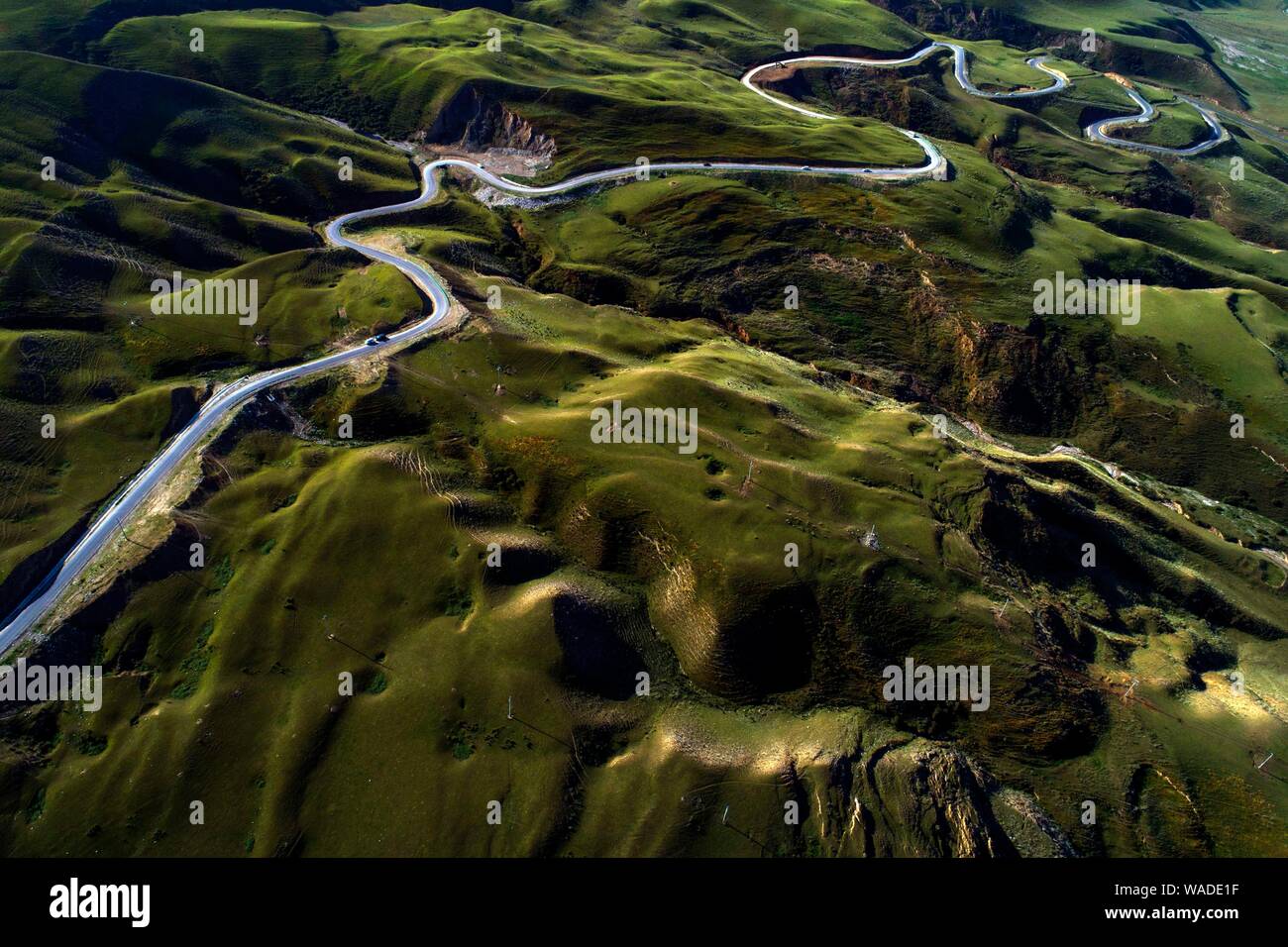 Cars drive on a spiral undulating mountain road at the Kalajun Scenic ...