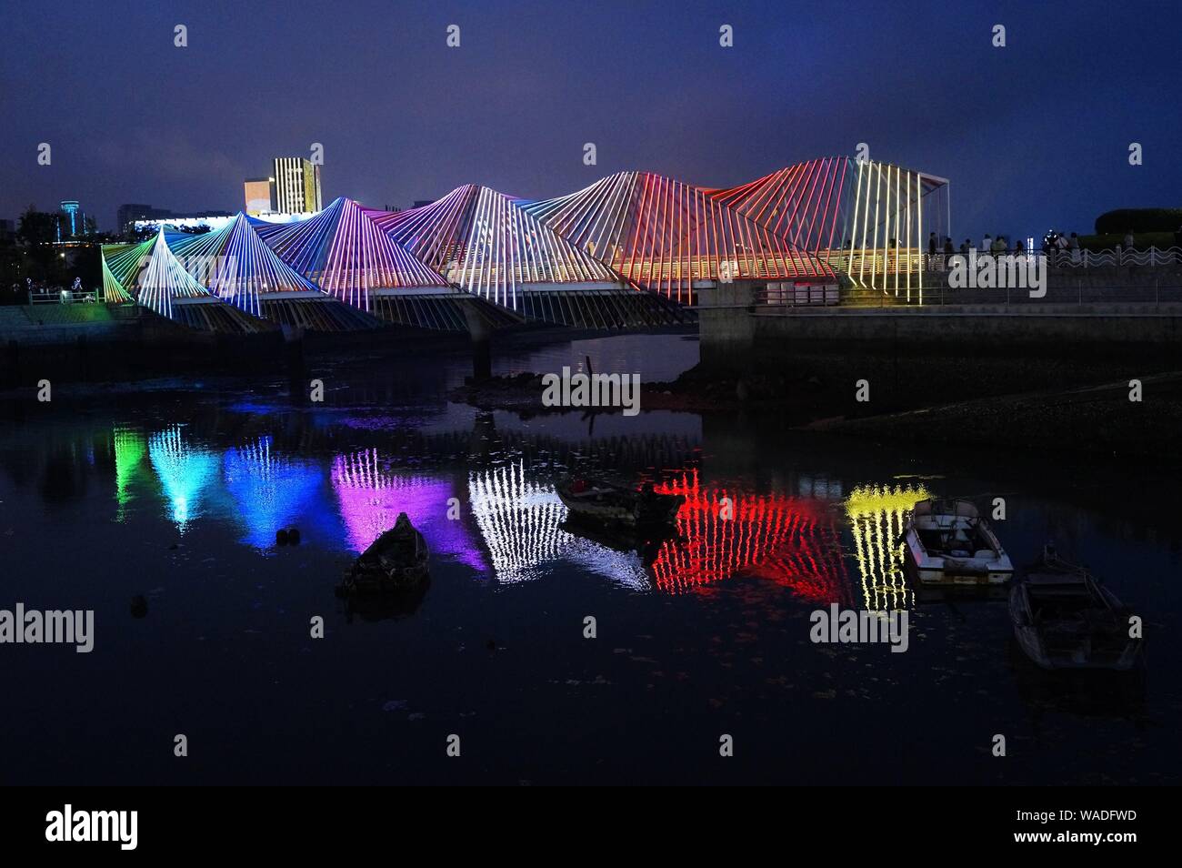 Local residents walk on the Rainbow Bridge illuminated by colorful ...