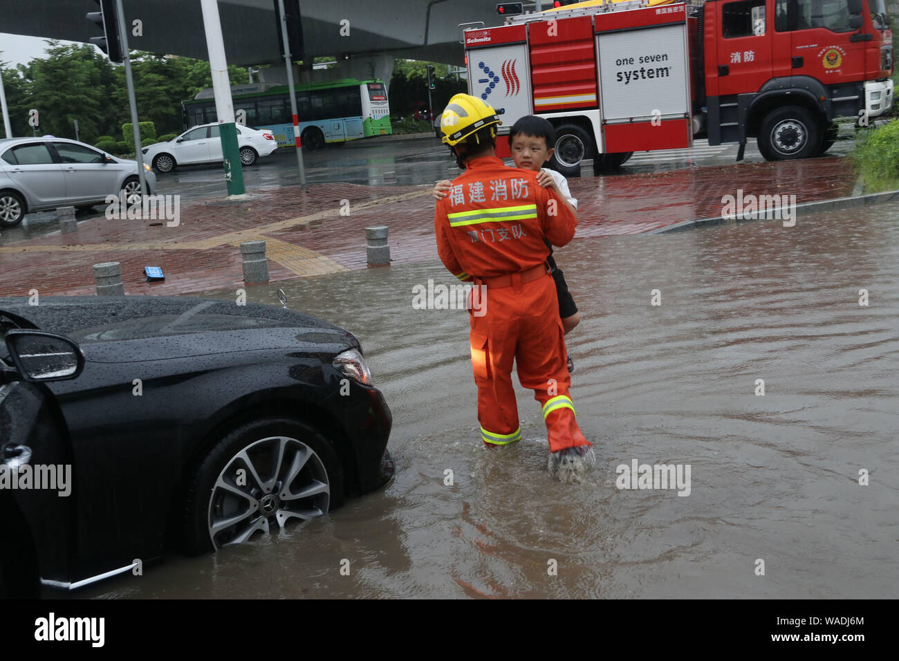 A Chinese rescuer evacuates a boy trapped in a car in floodwater caused ...