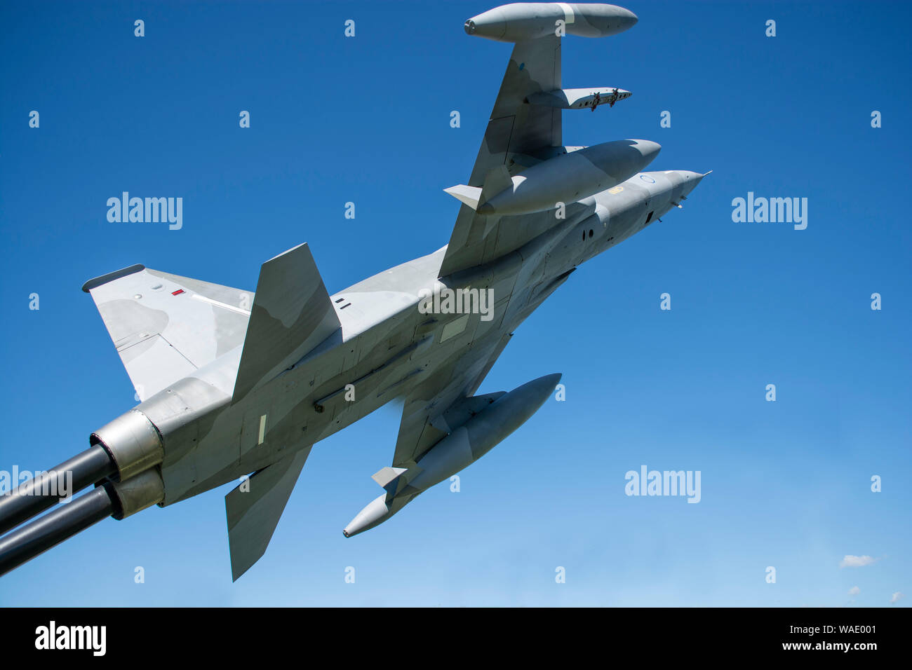 Fighter jet mounted for outdoor display. Against blue sky with upward ...