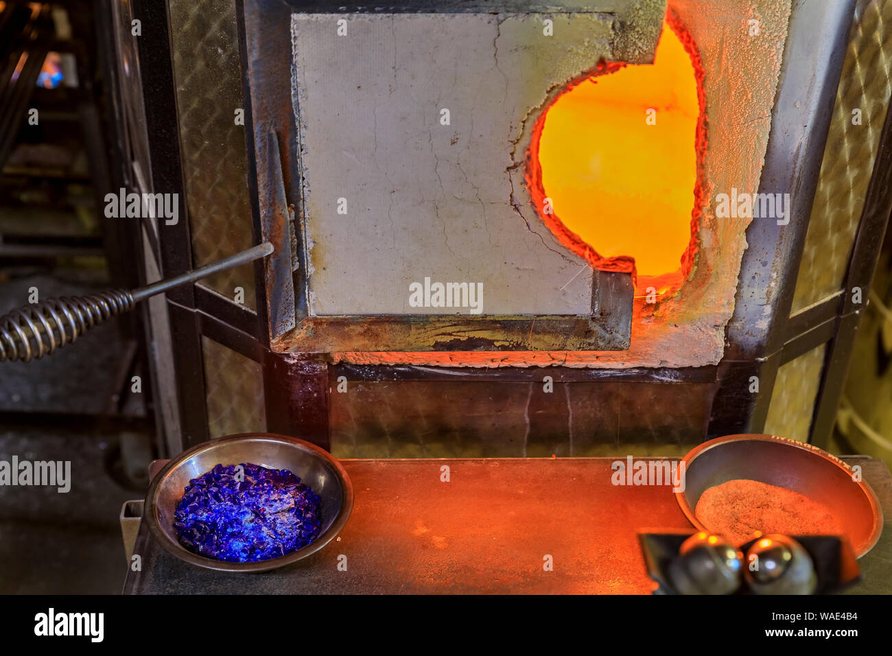 Glass blowing furnace and table with with crushed glass and tools at a ...