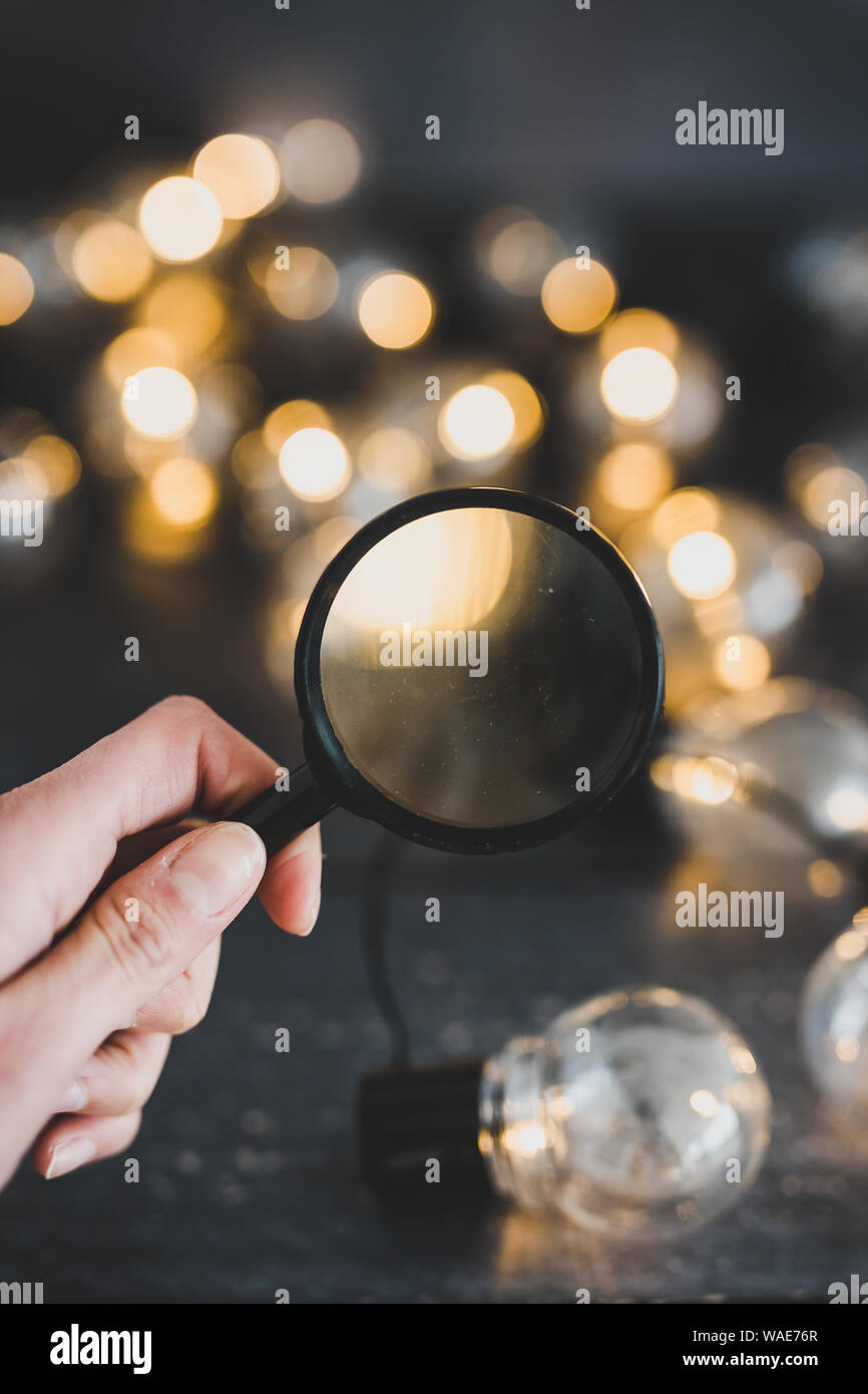 hand holding magnifying glass analyzing different ideas in shape of ...