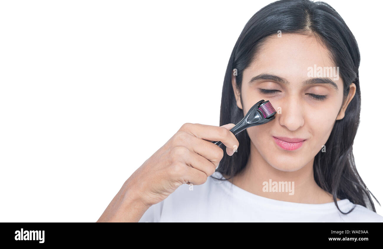 Close up of asian girl using derma roller on isolated white background ...