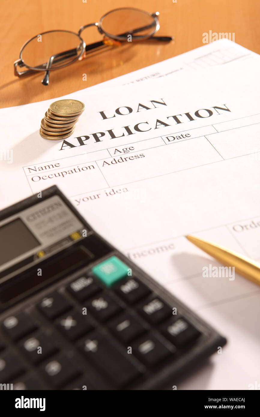 Pen and coins on loan application form Stock Photo - Alamy