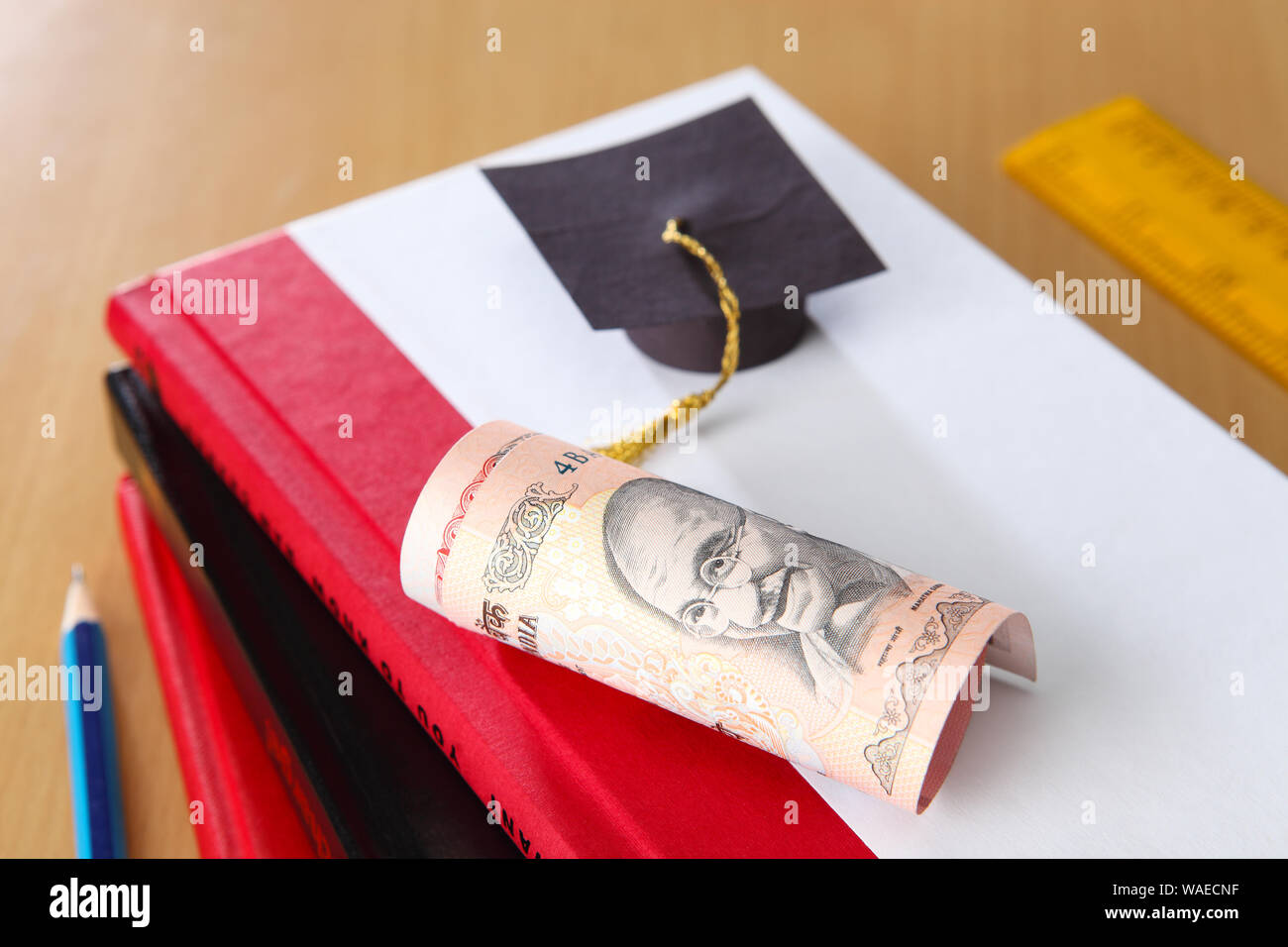 Mortar board and banknote on a stack of books Stock Photo - Alamy