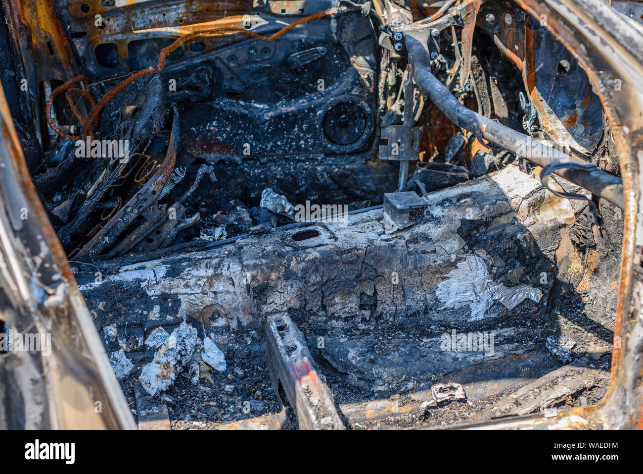 Burned car parked on the street, close-up. Abandoned burnt down car ...