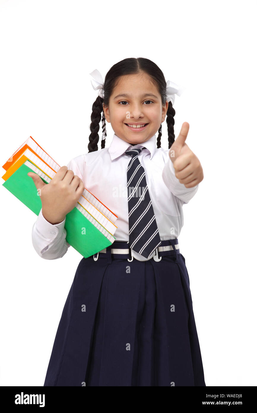 Schoolgirl standing with books and showing thumbs up sign Stock Photo ...