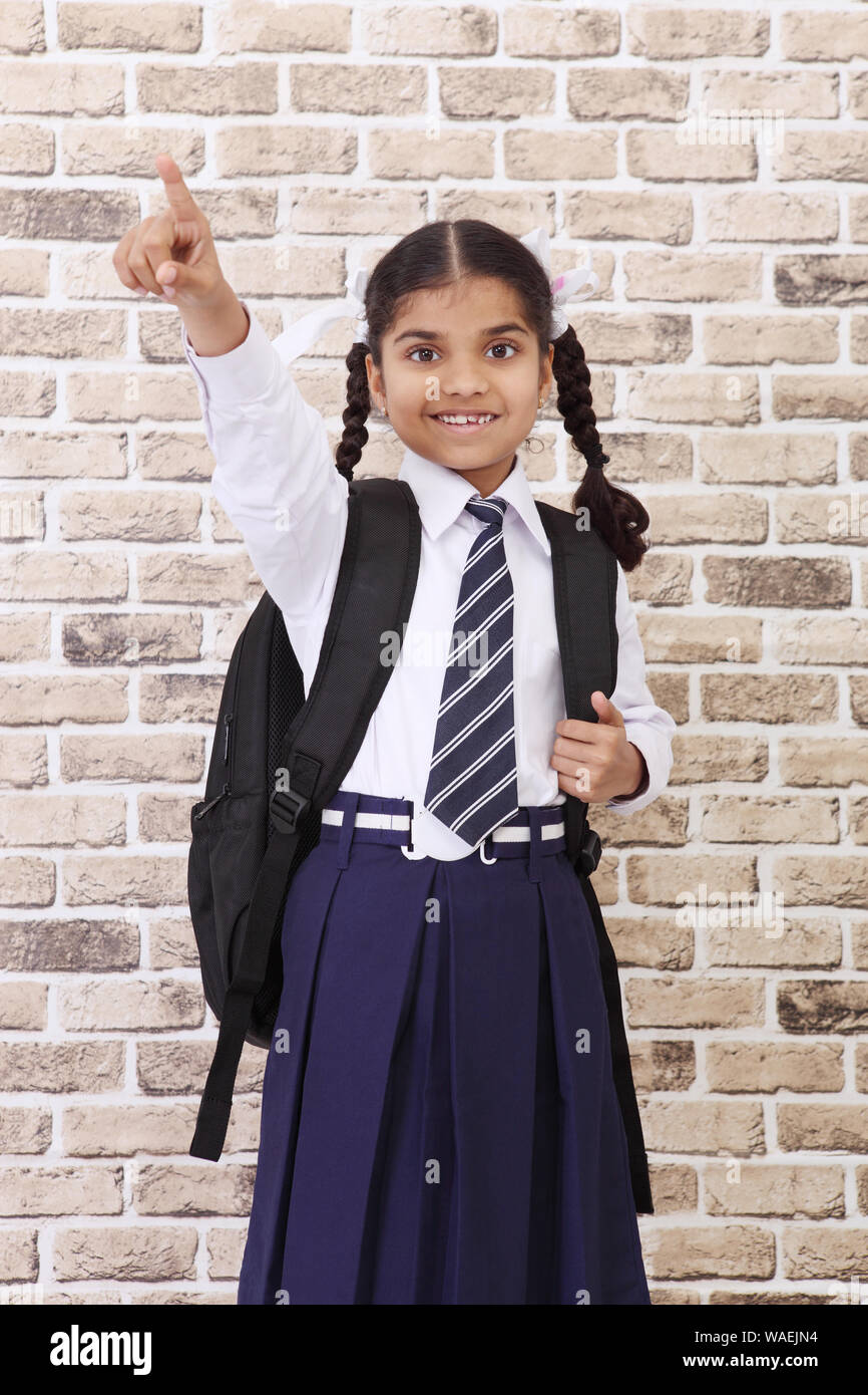 Schoolgirl standing with bag and pointing Stock Photo - Alamy