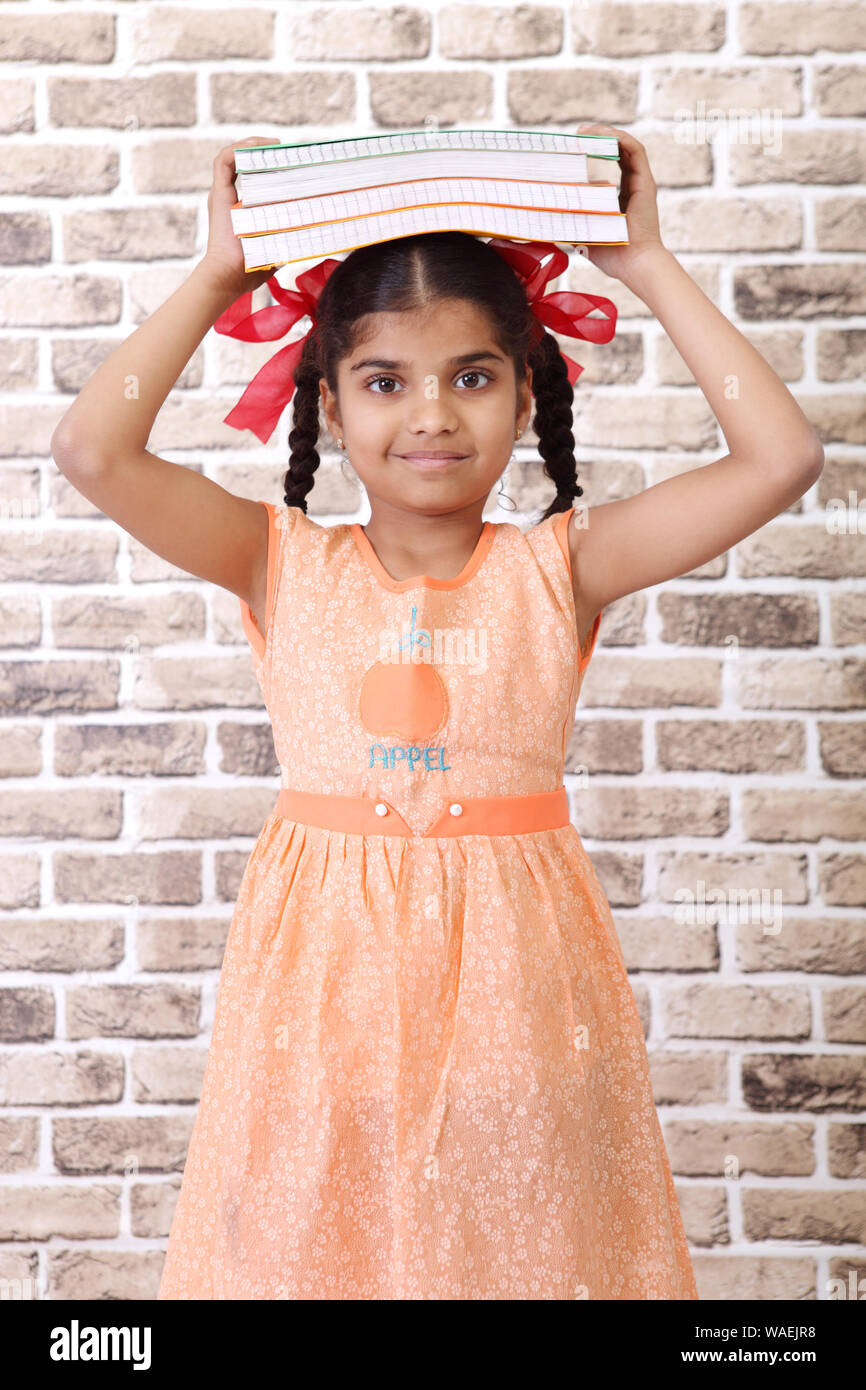 Girl carrying books on her head and smiling Stock Photo - Alamy