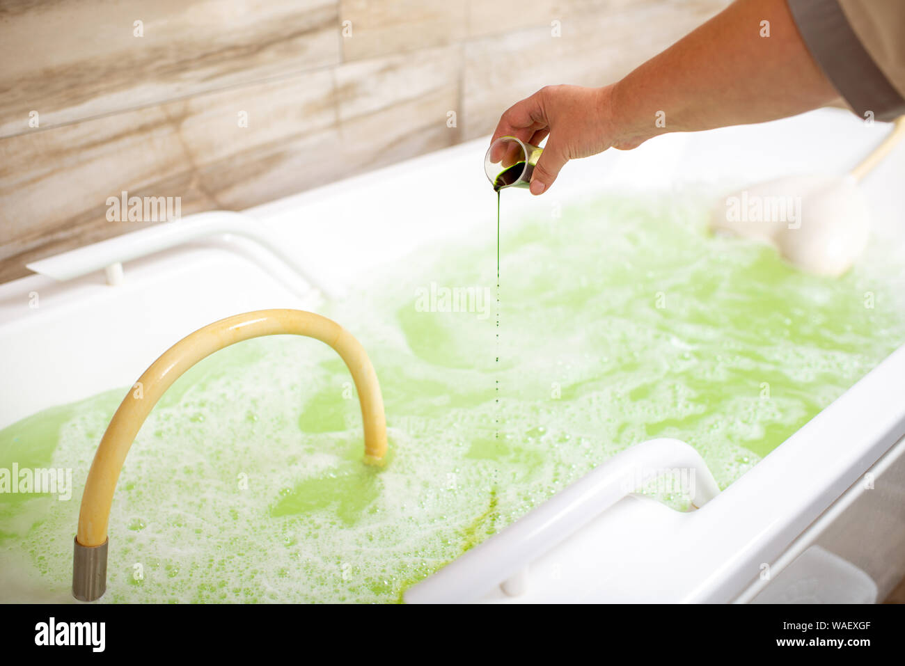 Pouring special ingredient for hydromassage into the tub filled with ...