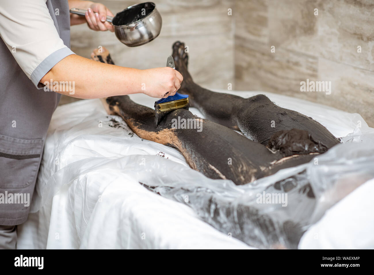 Man during a mud wrapping with special black mud, lying in the spa ...