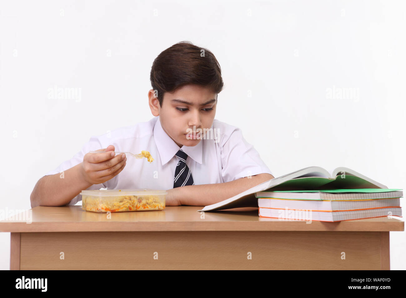 Schoolboy eating lunch in classroom and studying Stock Photo - Alamy