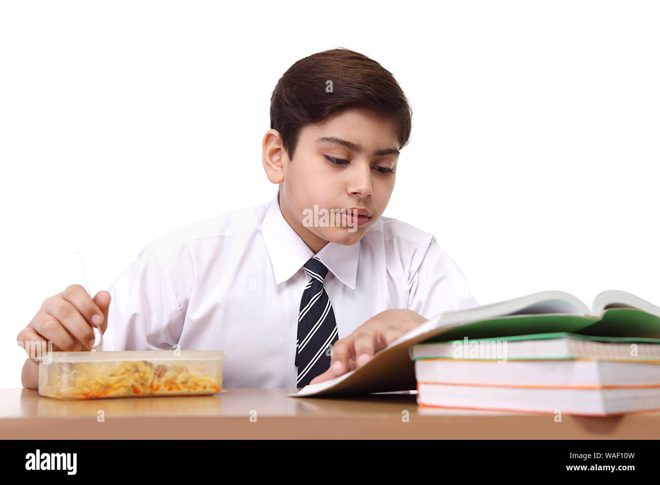 Schoolboy eating lunch in classroom and studying Stock Photo - Alamy