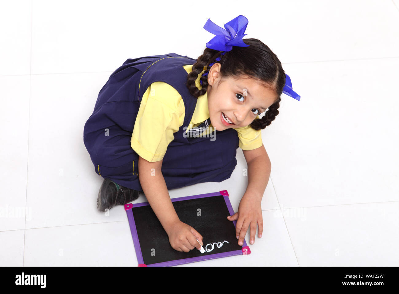 schoolgirl writing in a slate and smiling Stock Photo - Alamy