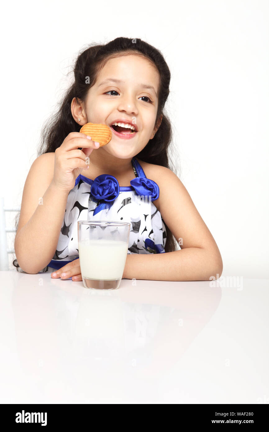 Girl eating biscuit with a glass of milk Stock Photo - Alamy