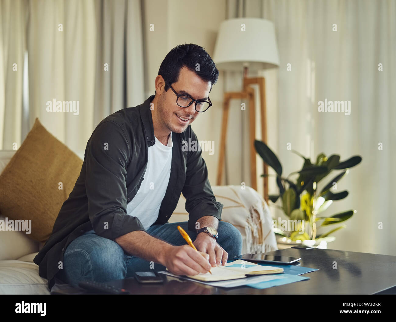 Happy man writing on notebook with pen at home Stock Photo - Alamy