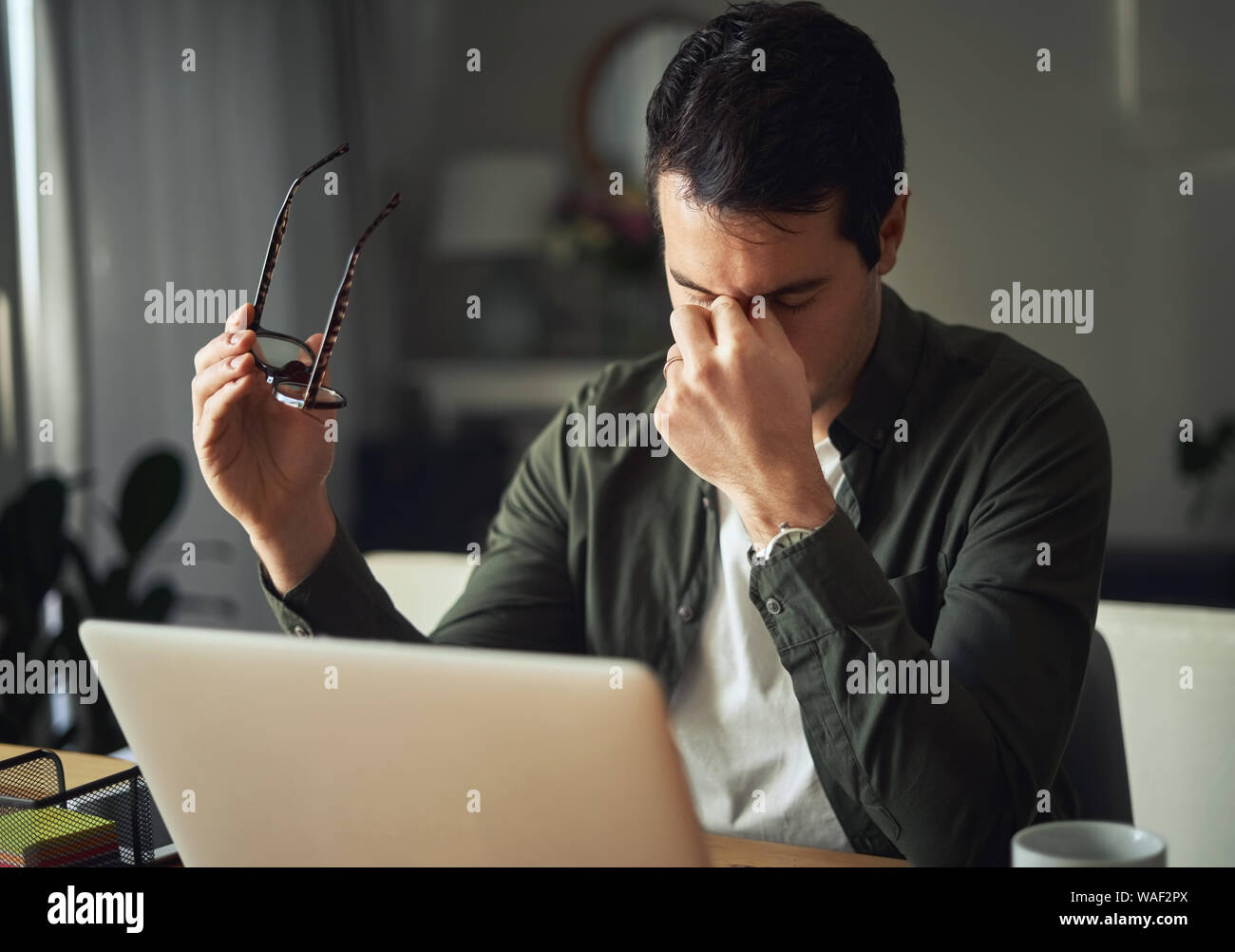 Tired take glasses off working too long at computer Stock Photo - Alamy