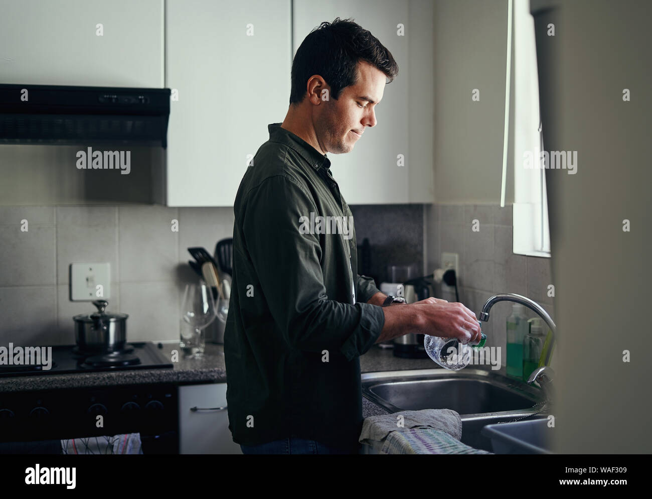 Man washing glassware in the kitchen sink Stock Photo - Alamy