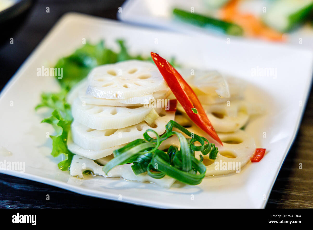 Sliced lotus root with spring onion and chilli on a plate Stock Photo ...