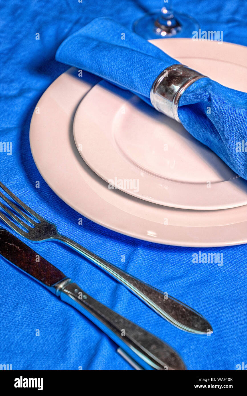 table setting with plates, napkin, silverware in bright blue color ...