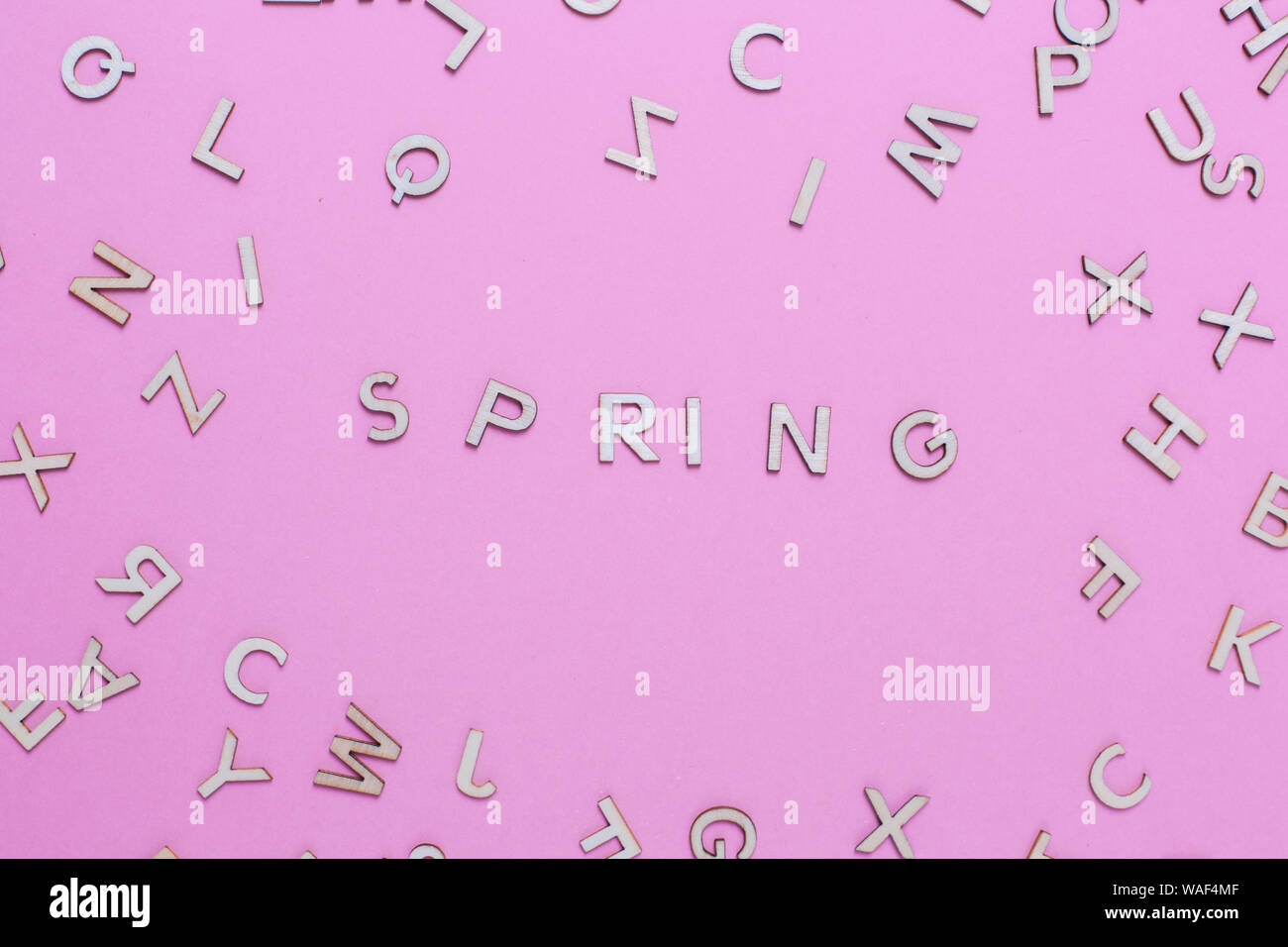 Wooden ABC alphabet letters on pink background. Spring word written ...