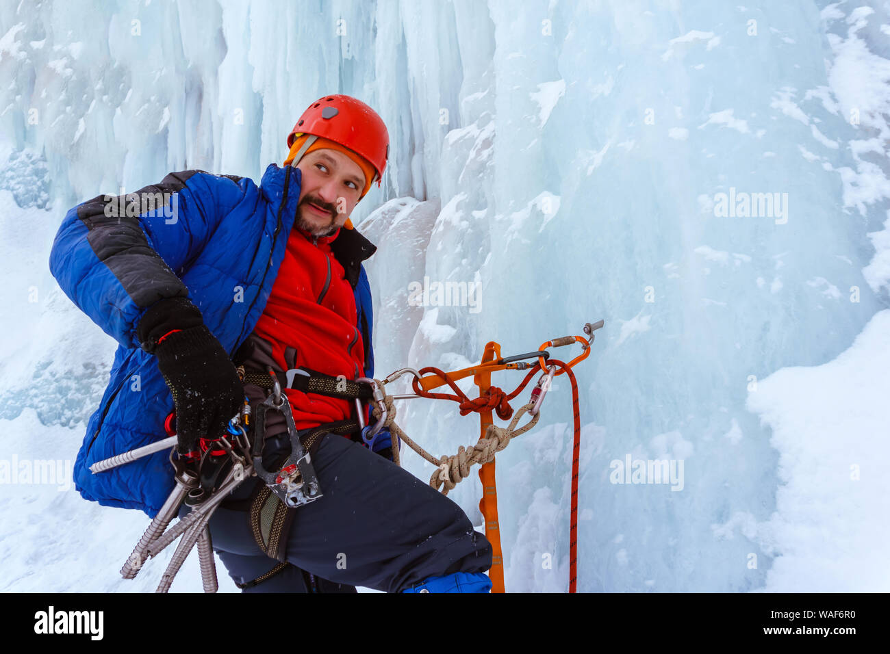ice climber is fixed on the vertical surface of the glacier with safety ...