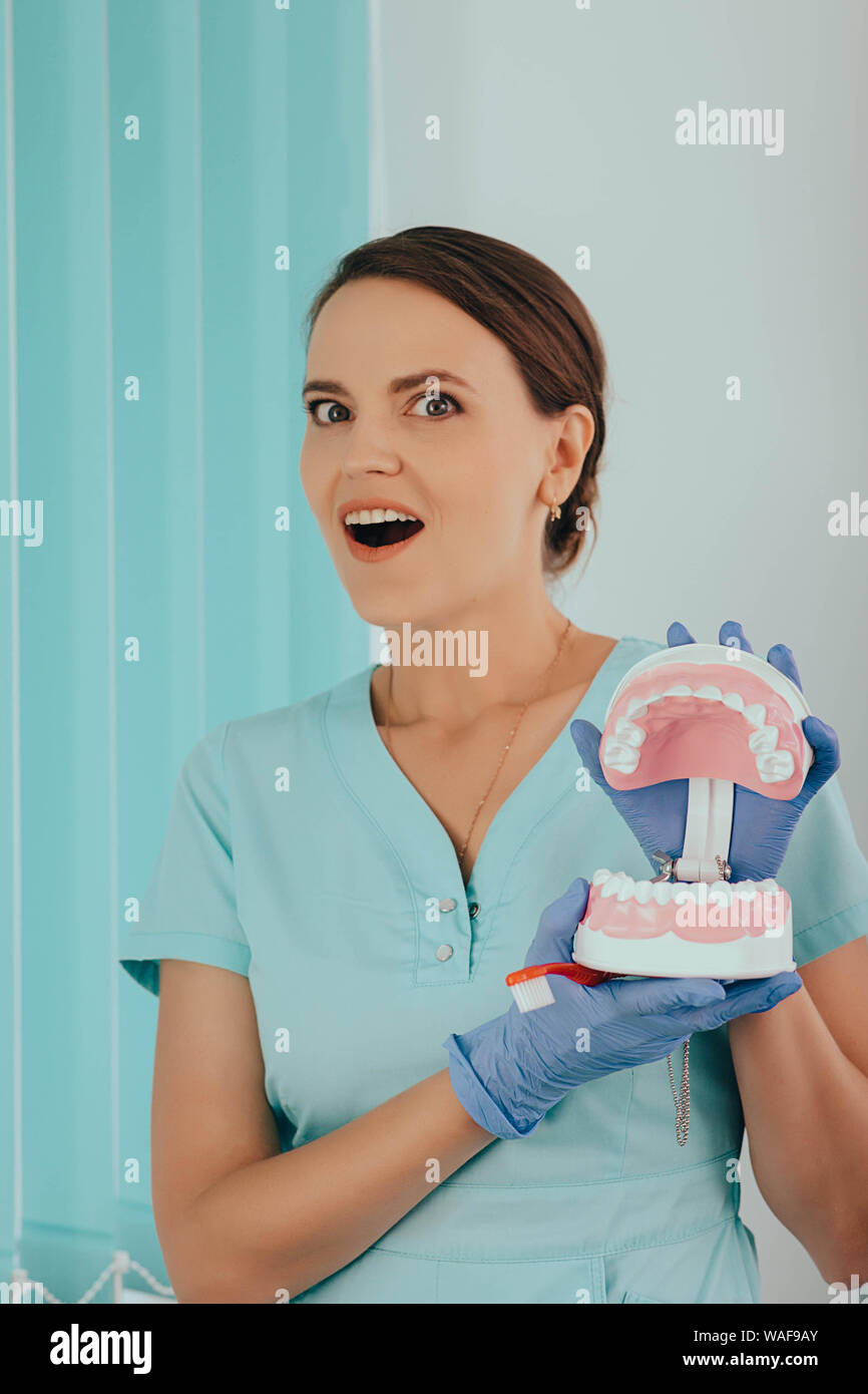 Portrait of shocked dentist woman looking at camera, holding tooth ...