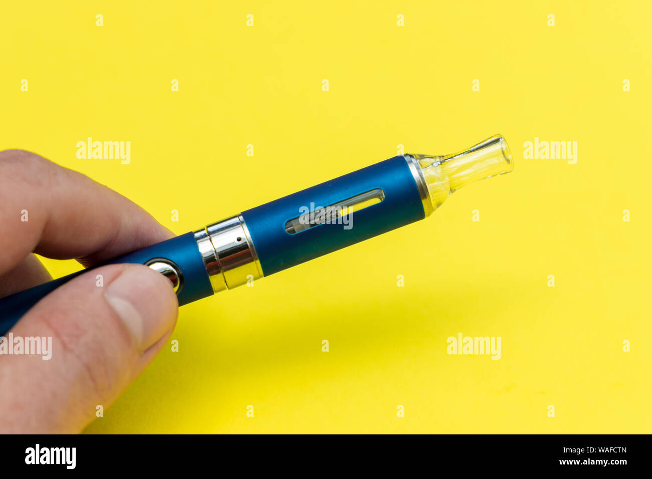 Hand holding vape pen metal electronic cigarette with vaping yellow ...