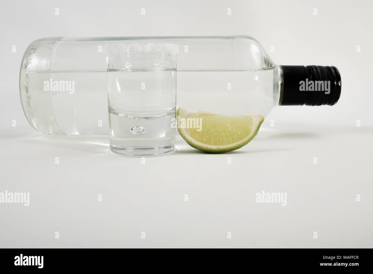 Detail of tequila served in a glass with a slice of lemon and a bottle ...