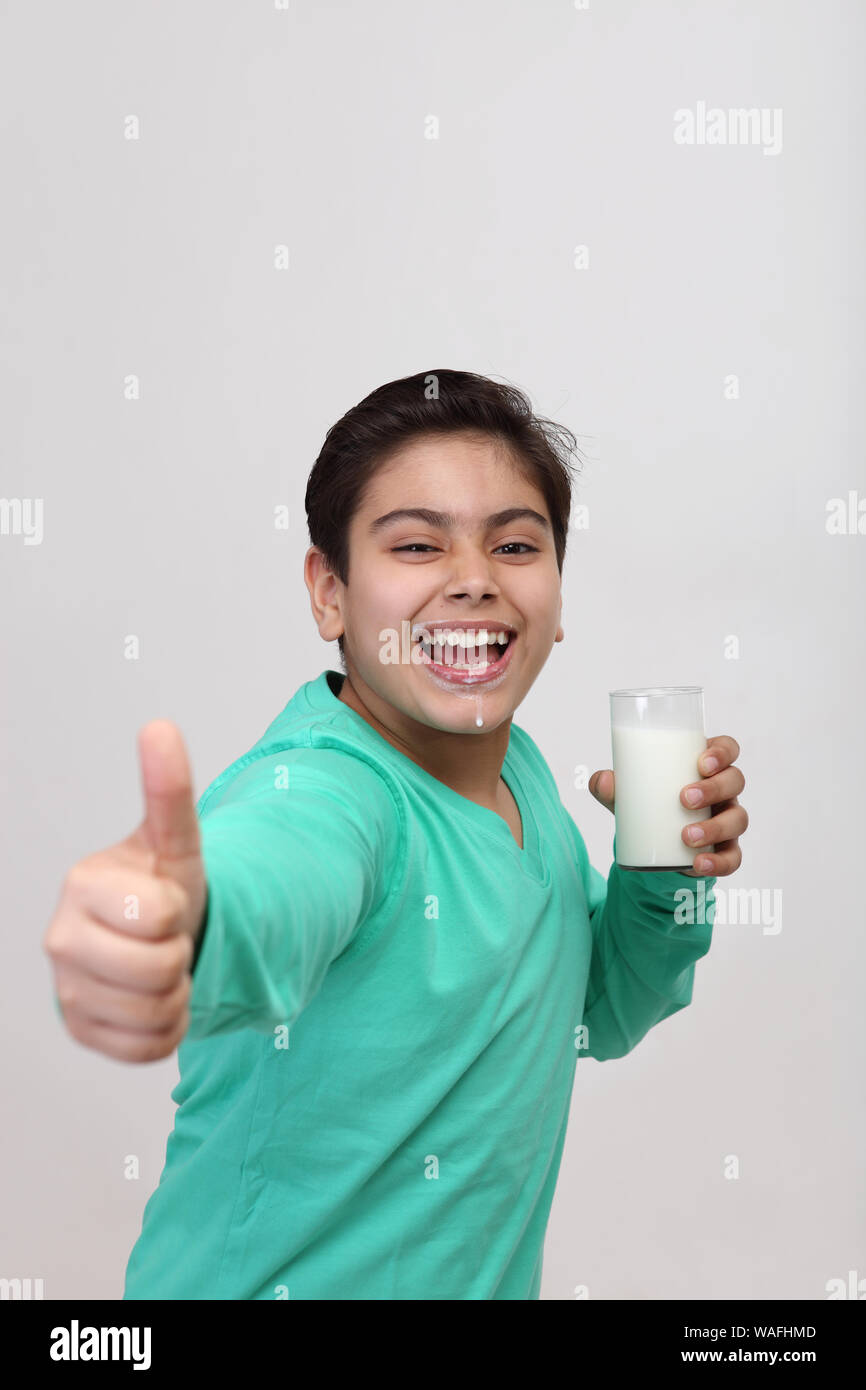 Boy drinking a glass of milk and showing thumbs up Stock Photo - Alamy