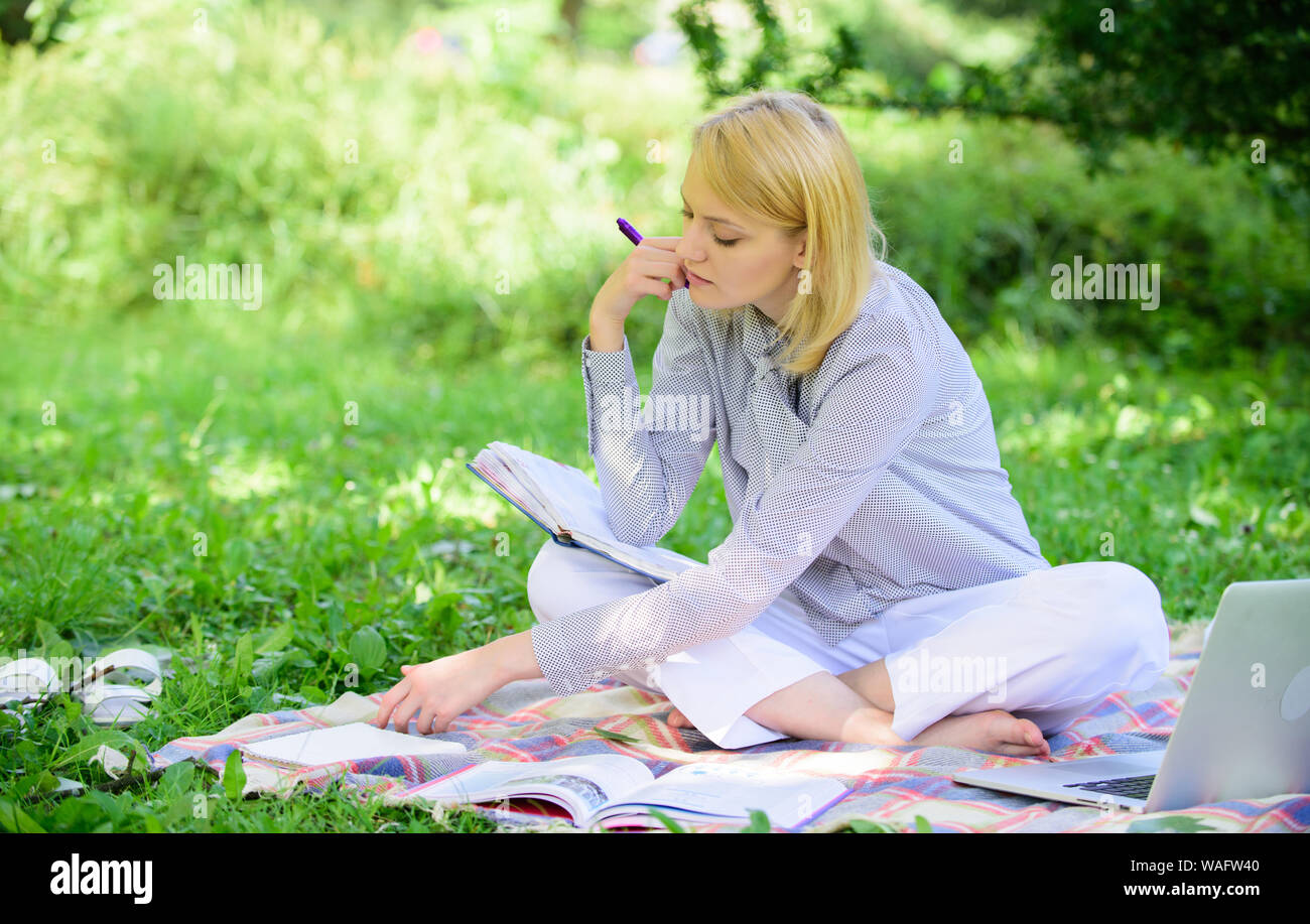 Woman with laptop sit on rug grass meadow. Girl with notepad write note ...