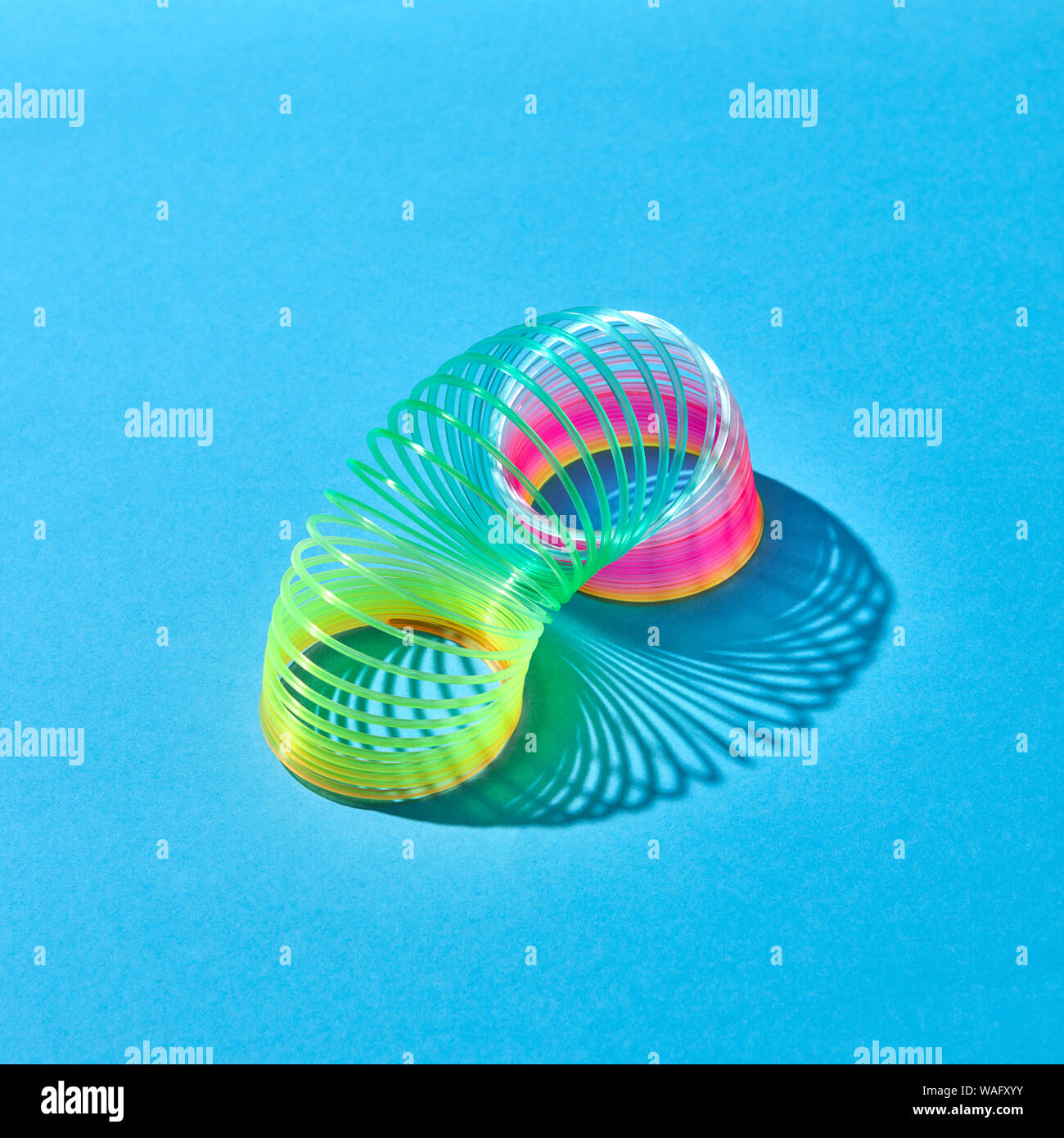 Colorful flexible spring with shadows on a pastel blue background with ...