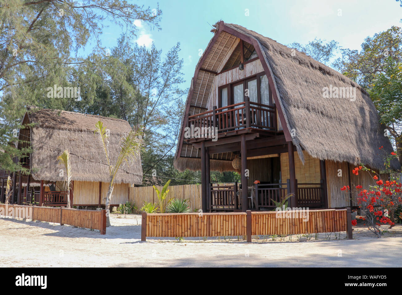 Traditional Indonesian bungalow on white sand beach in tropical ...