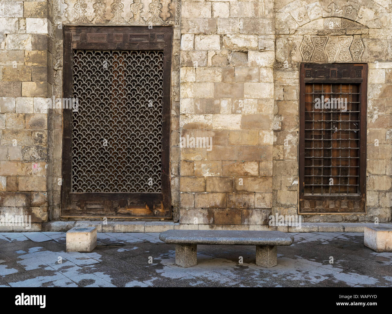 Two wooden windows with decorated iron grid over stone bricks wall and ...