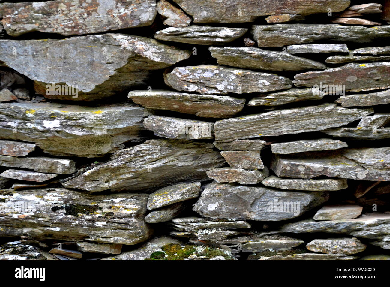 Close-up detail view of an old traditional stone wall built from schist ...