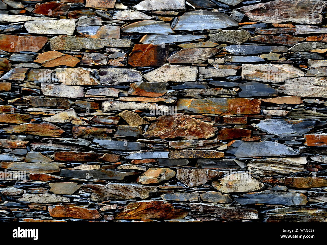 Close-up detail view of an old traditional stone wall built from schist ...