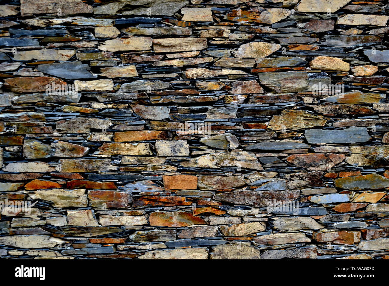 Close-up detail view of an old traditional stone wall built from schist ...