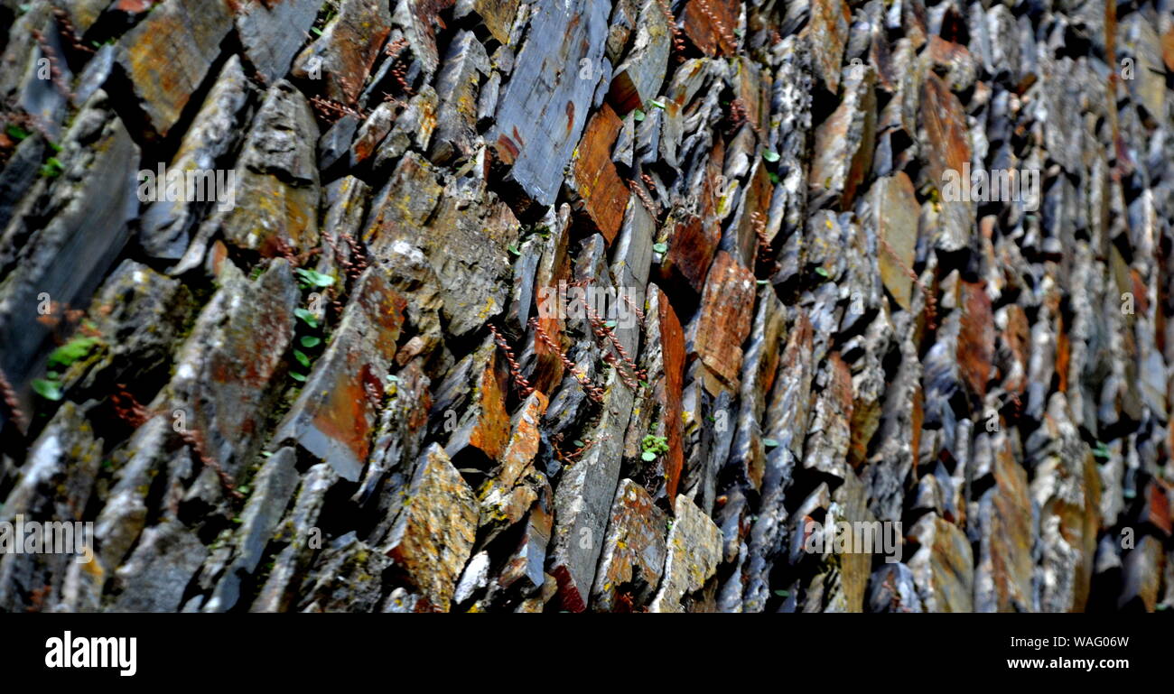 Close-up detail view of an old traditional stone wall built from schist ...