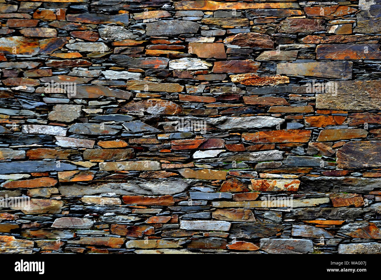 Close-up detail view of an old traditional stone wall built from schist ...