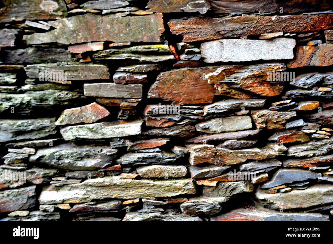 Close-up detail view of an old traditional stone wall built from schist ...