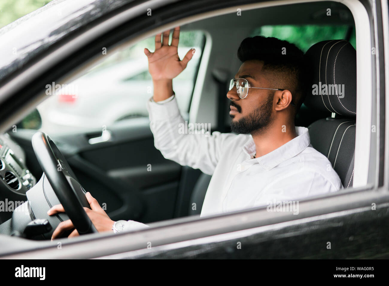 Rear view of young man driving a car and looks angry, shouting inside ...